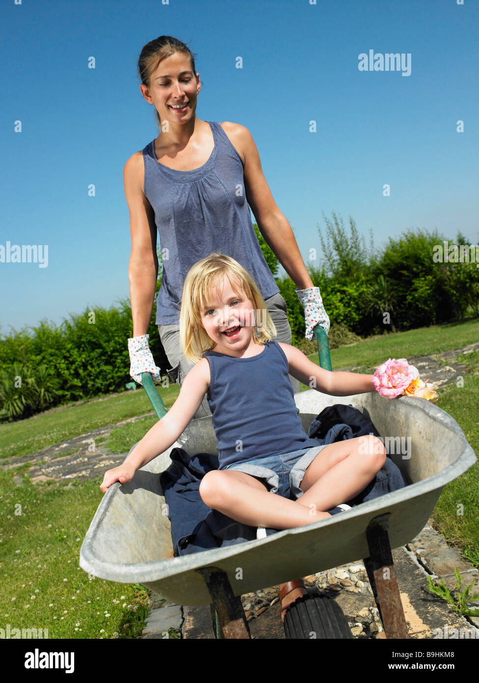 Girl in wheelbarrow, pushed by a woman Stock Photo - Alamy