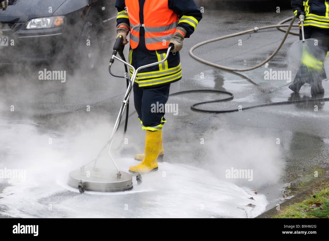 Fire brigade in action, neutralising leaked brake fluid with cleaning ...