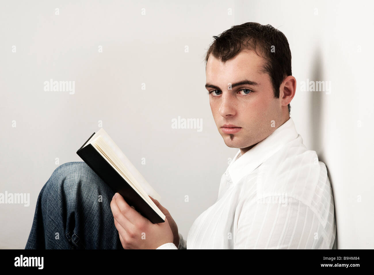 Young man holding a book, looking at the camera Stock Photo - Alamy