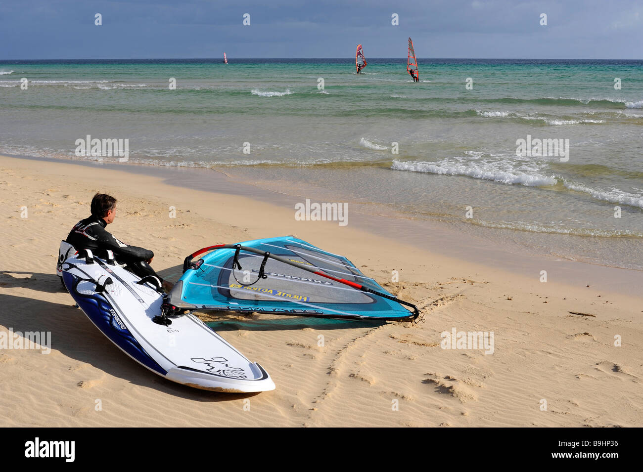 Windsurfer sitting on the Playa de Sotavento de Jandia Beach, watching ...