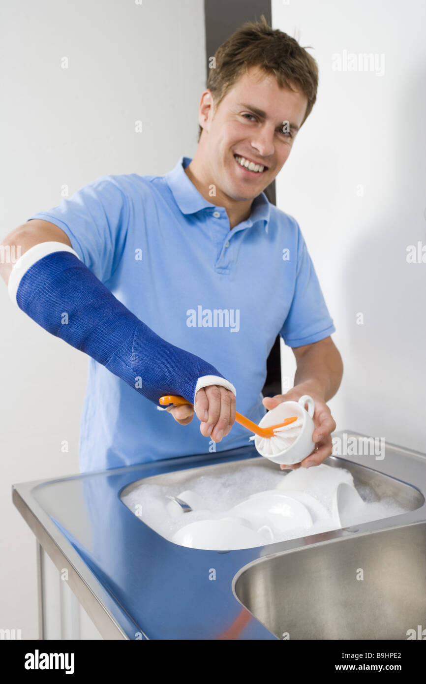 Man arm in plaster dishes does dishes smiling series people arm injury ...