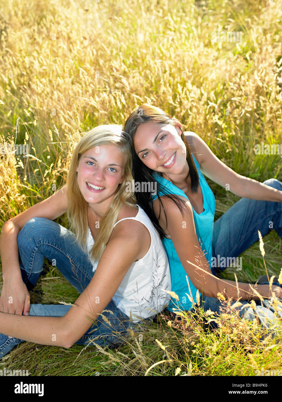 Girls seated in a field, smiling Stock Photo - Alamy