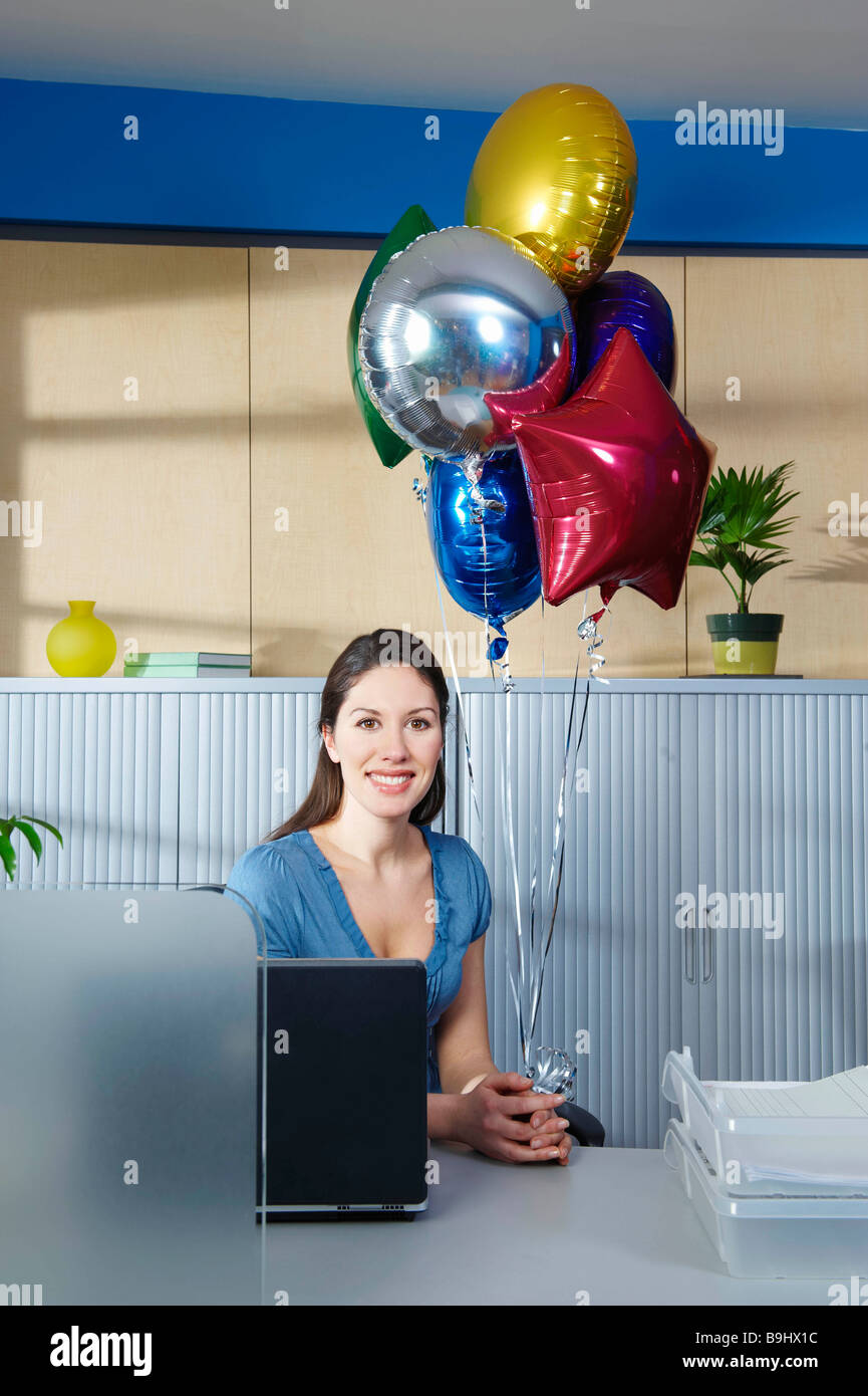 Young woman with balloons at desk Stock Photo - Alamy
