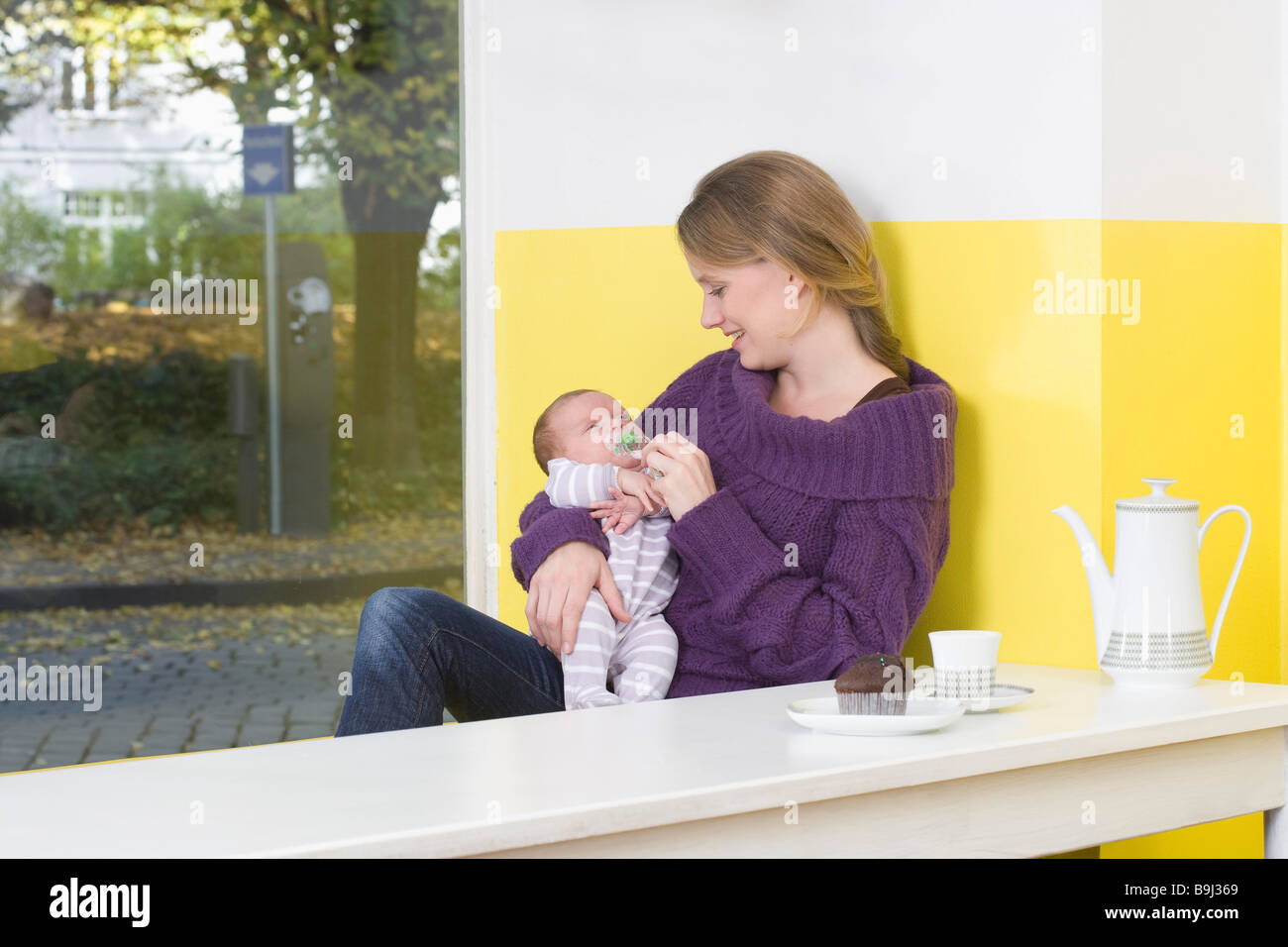 Young woman with baby on table Stock Photo - Alamy