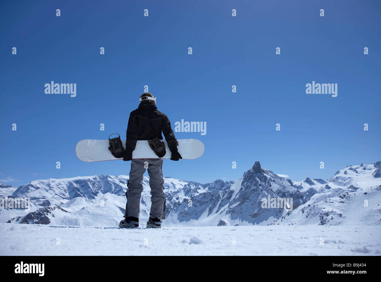 Man standing on mountain with snowboard Stock Photo - Alamy