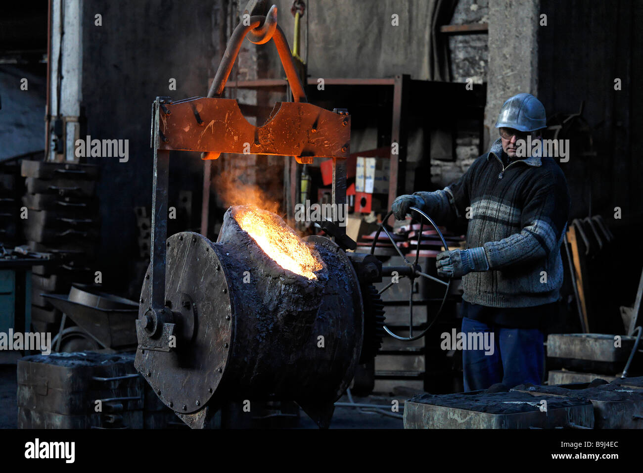 Founder tipping small crane ladle with molten iron, historical iron ...