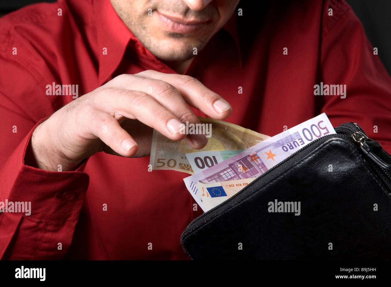 Young man happily looking into his full wallet Stock Photo - Alamy