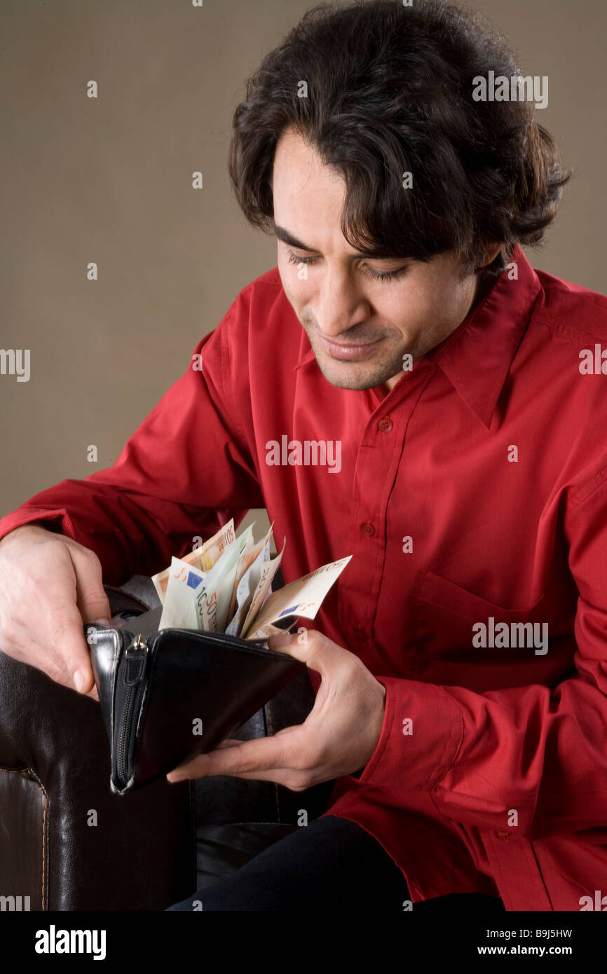Young man looking at his full wallet, pleased Stock Photo - Alamy