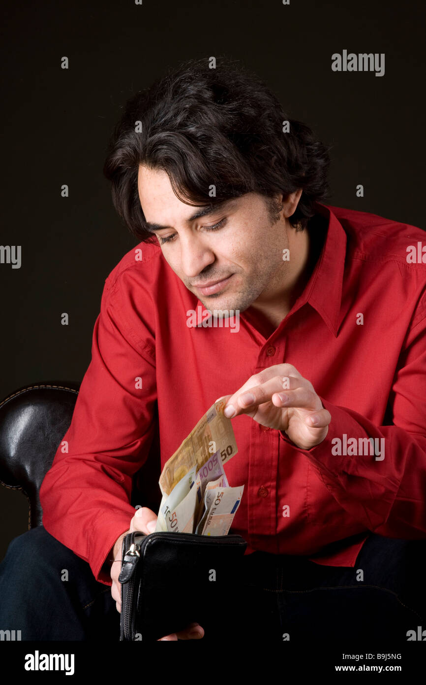 Young man contently looking into his full wallet Stock Photo - Alamy