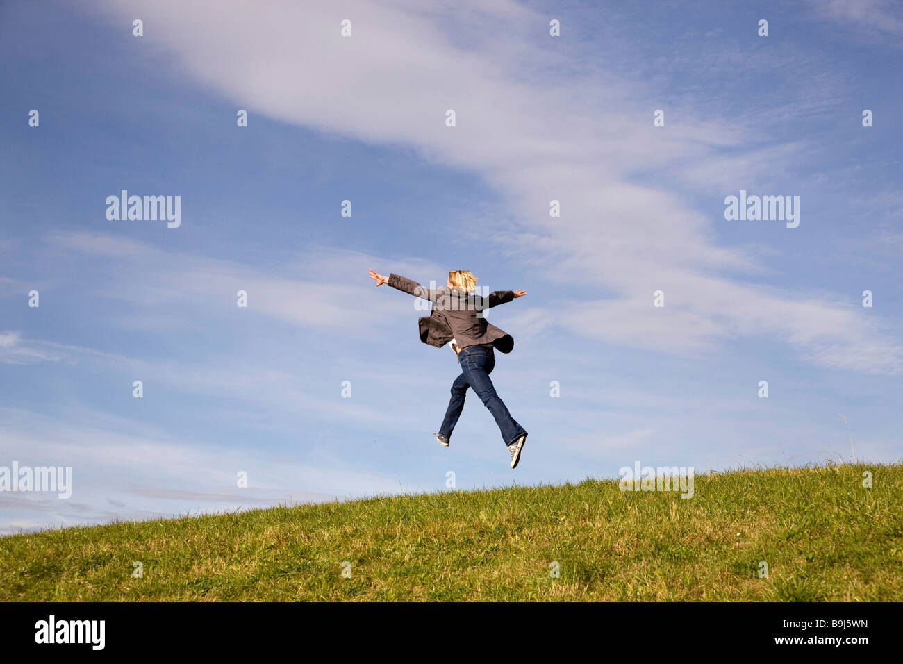Man jumping into distance on grass Stock Photo - Alamy