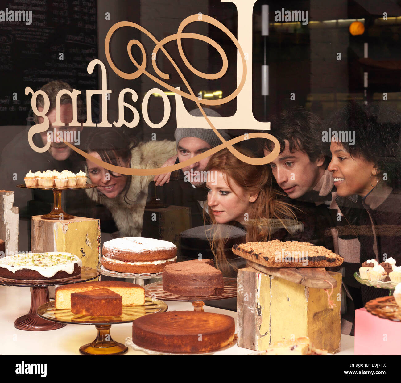 Group of friends looking through window Stock Photo - Alamy