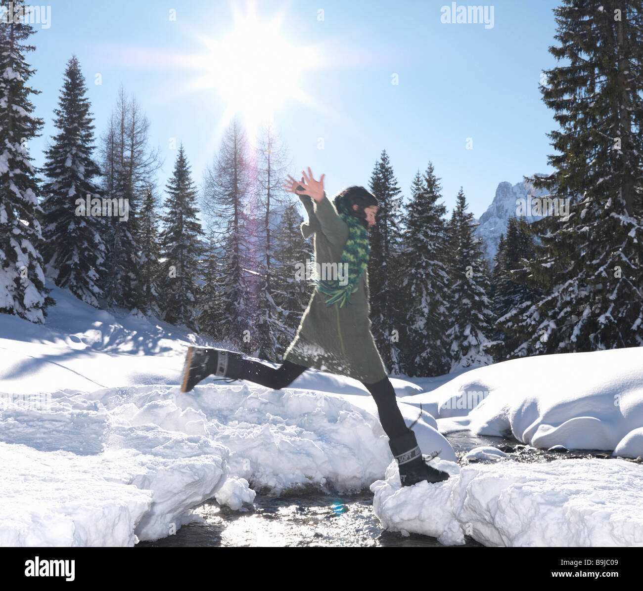 Woman jumping across stream Stock Photo - Alamy