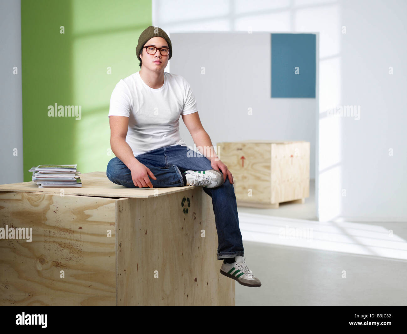 Young man sitting on box Stock Photo - Alamy