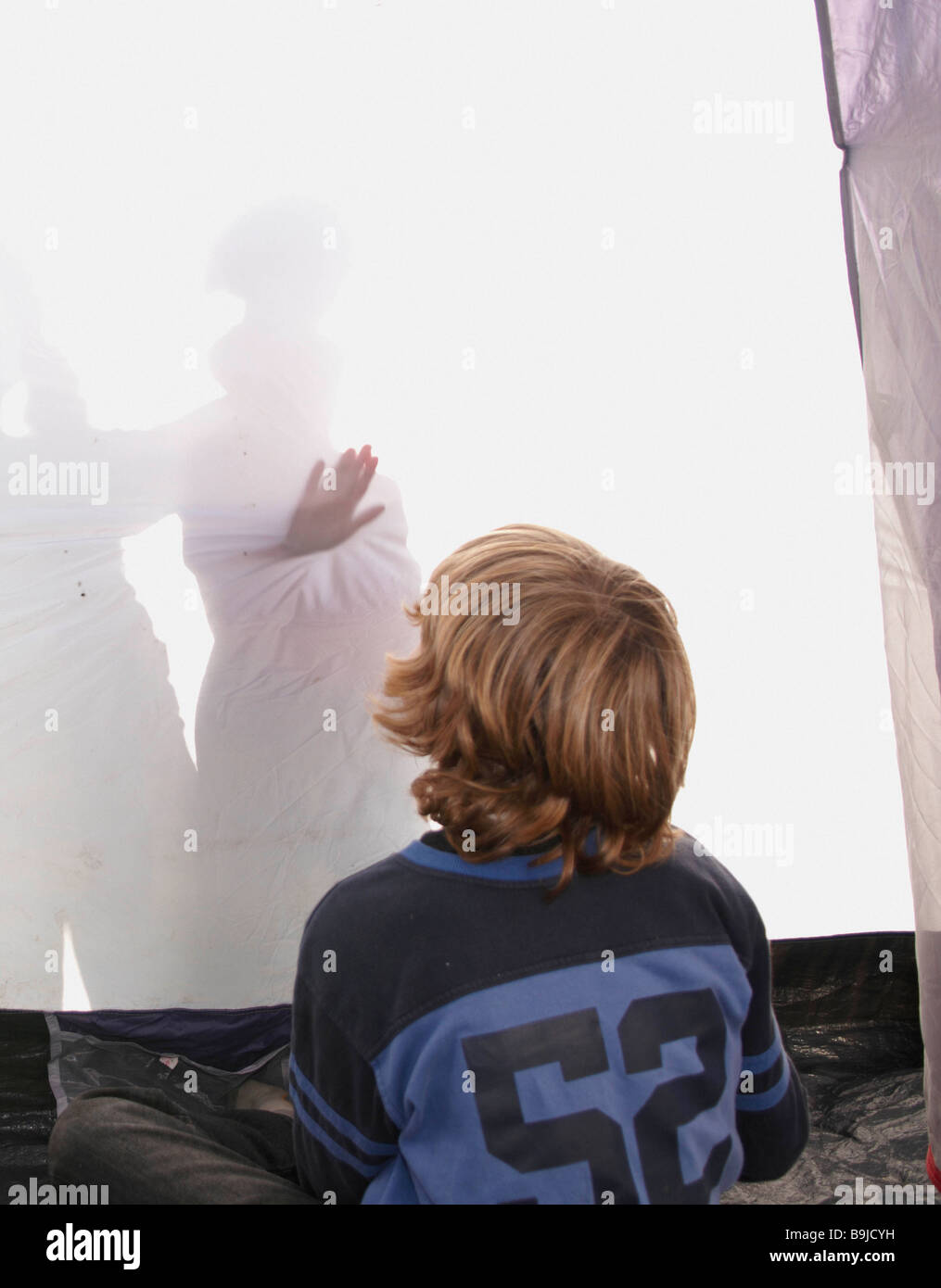 Boy looking at shadows in tent Stock Photo - Alamy