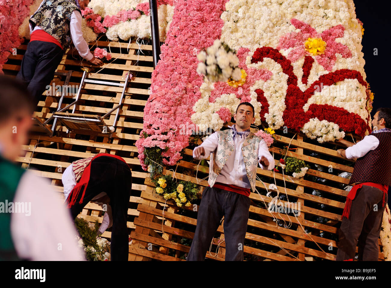 Men placing flower offerings on large wooden replica statue of Virgen ...