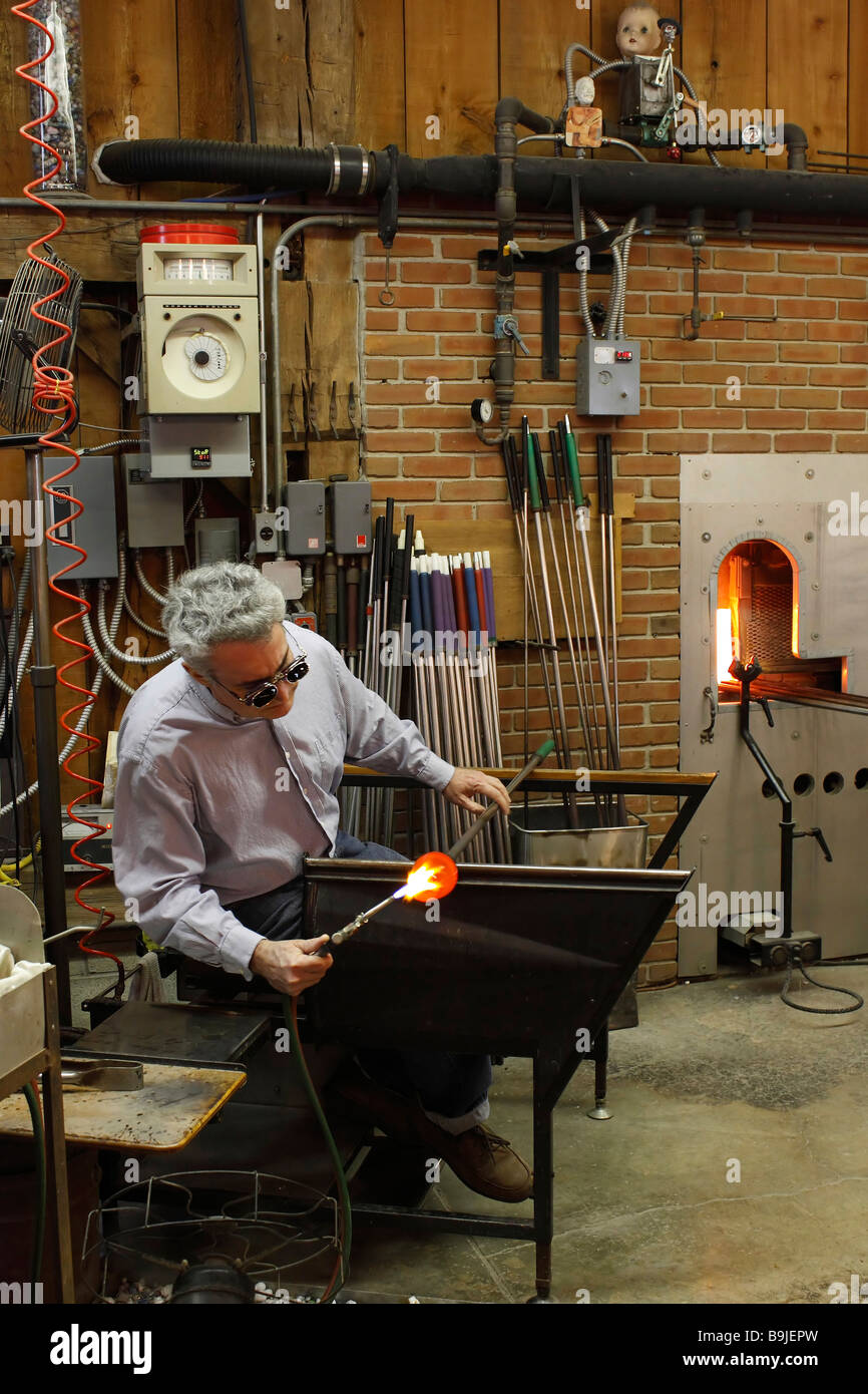 Master glassmaker making in the glassworks with glass furnace close up ...