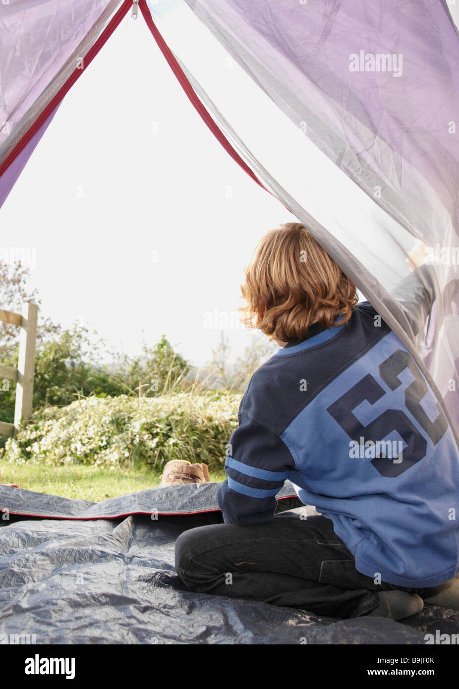 Boy looking out of tent Stock Photo - Alamy
