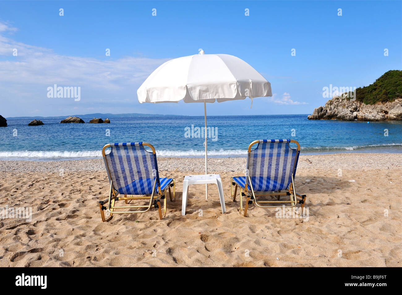 Two empty sun loungers and a parasol on the deserted beach in Sarakina ...