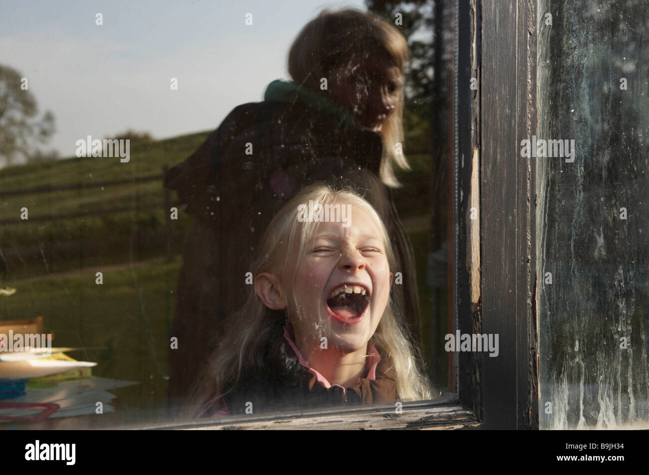 Girl laughing through window Stock Photo - Alamy