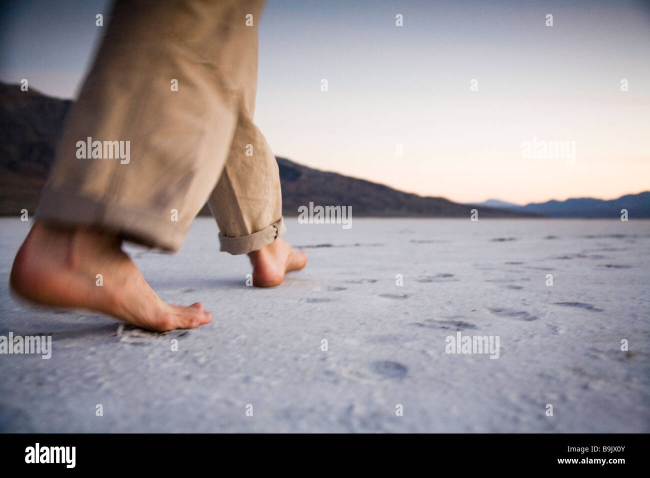 A man walks barefoot on the salt flats of Death Valley National Park ...