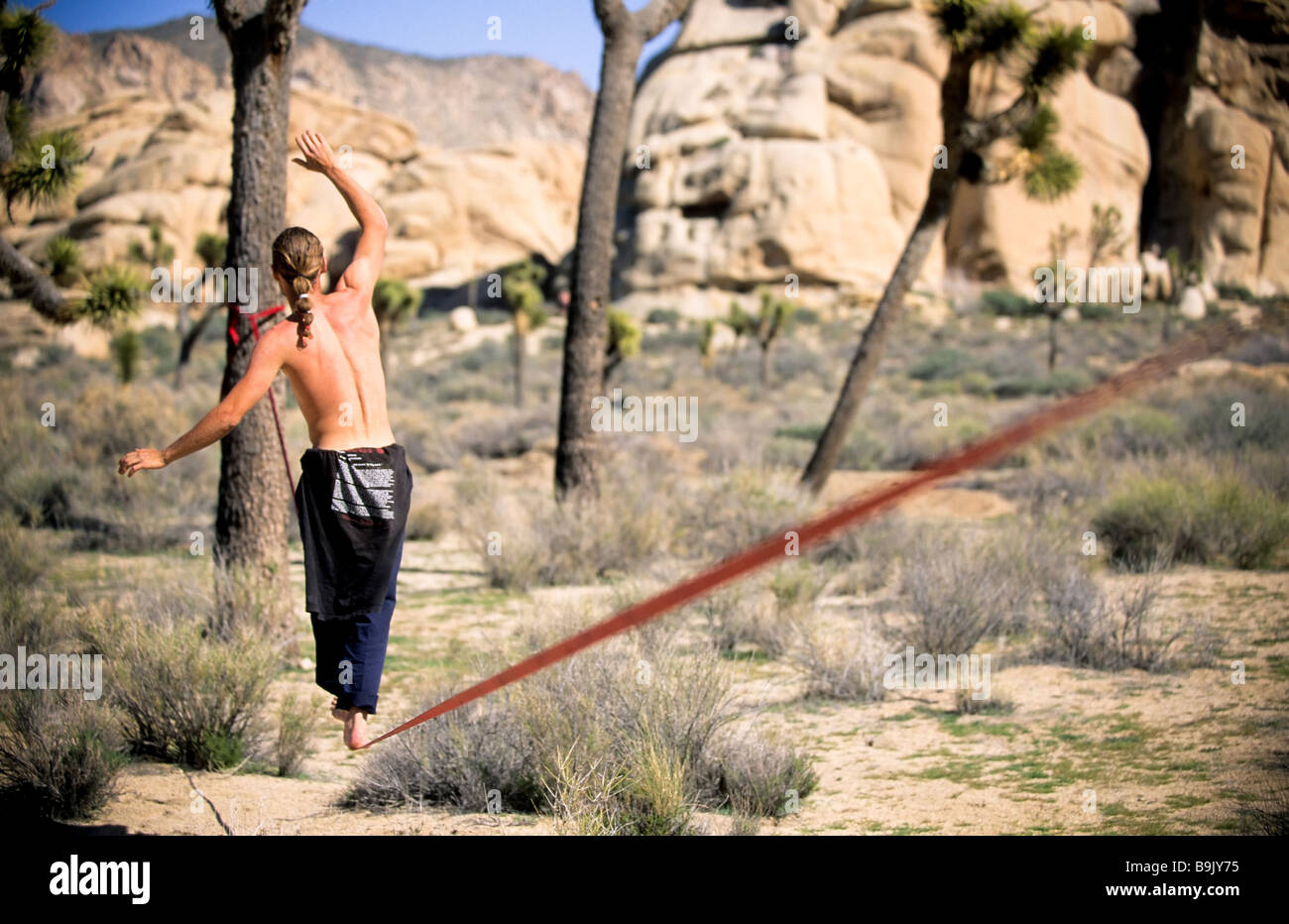 A man uses his arms to maintain balance while tight rope walking or ...