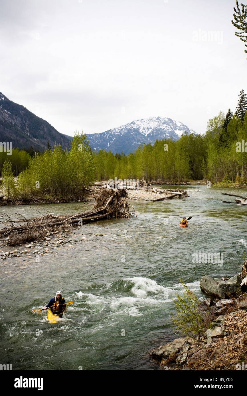 Two kayakers enjoy calm whitewater on a remote river in Washington ...