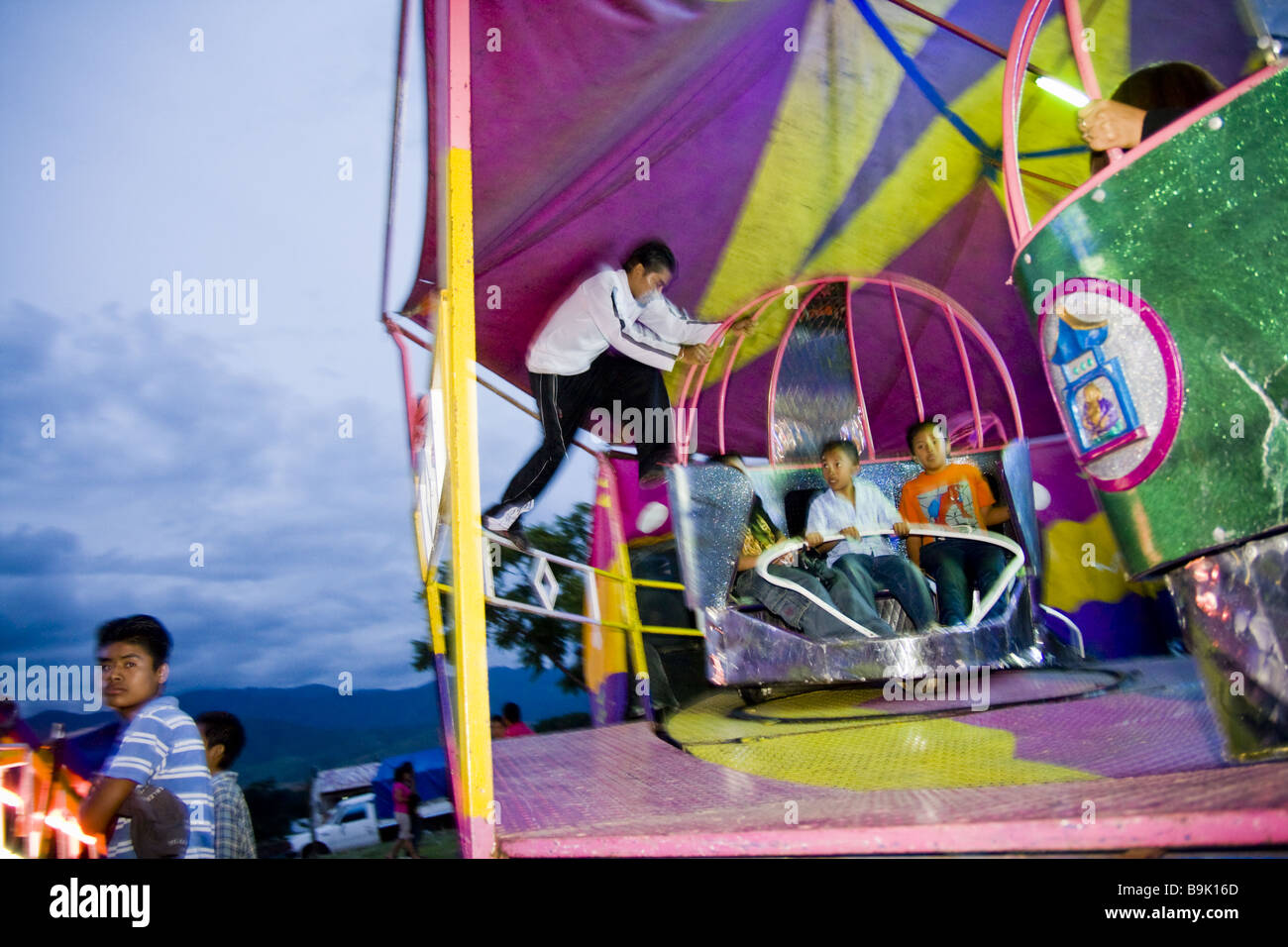 A young man leaps from car to car as children swirl past on a carnival ...