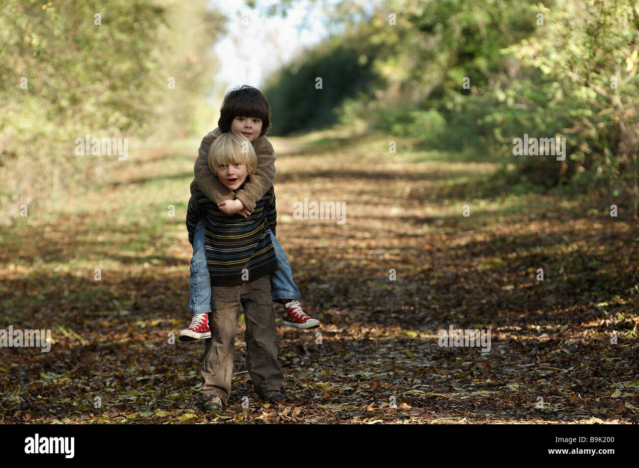 Young boy carrying friend in countryside Stock Photo - Alamy