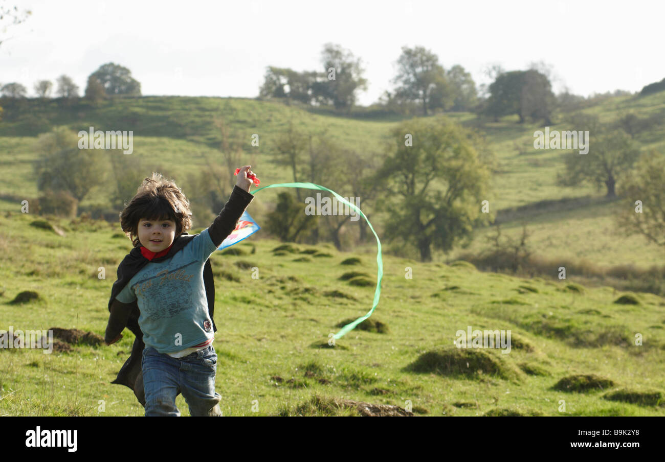 Young boy running with kite in field Stock Photo - Alamy