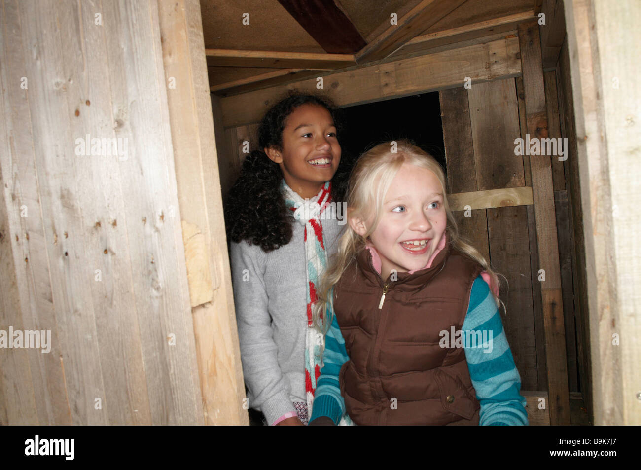 Two young girls enter treehouse Stock Photo - Alamy