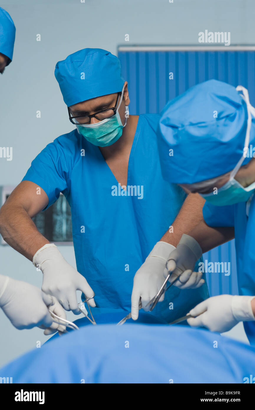 Three surgeons performing a surgery in an operating room Stock Photo ...