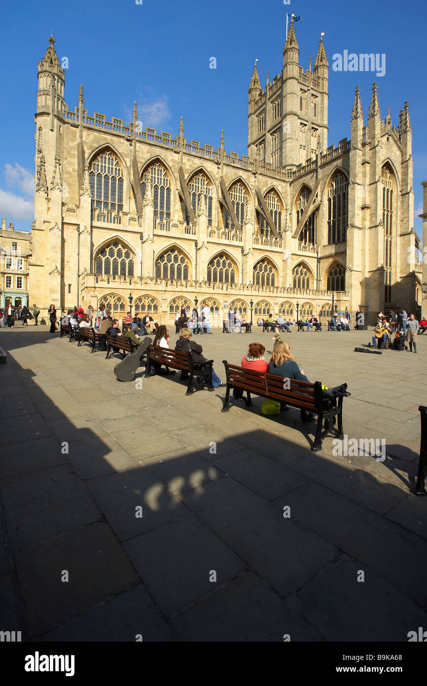 People sitting in the sunshine watching a busker perform outside Bath ...