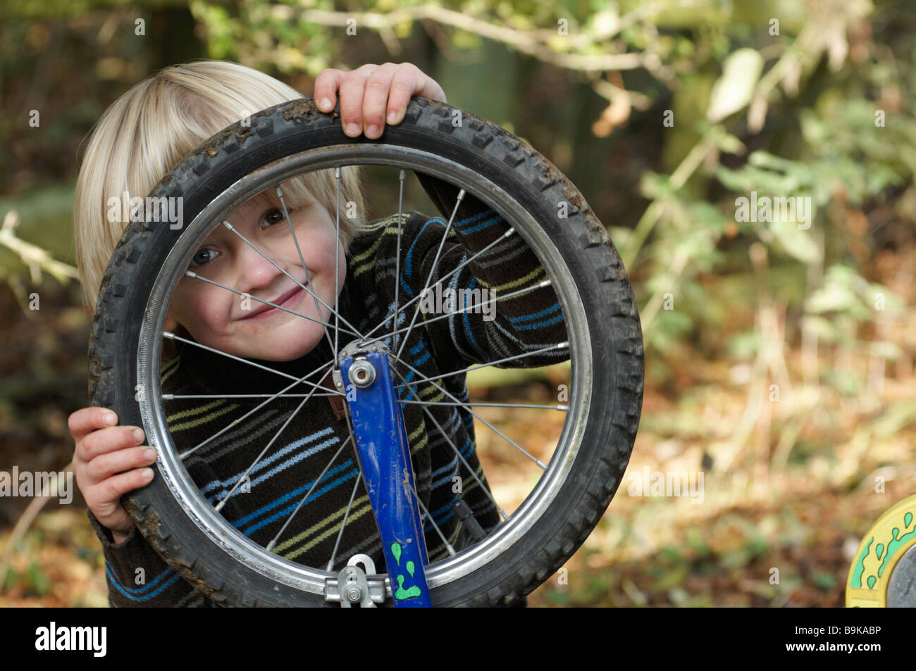 Boy looking through bike wheel Stock Photo - Alamy