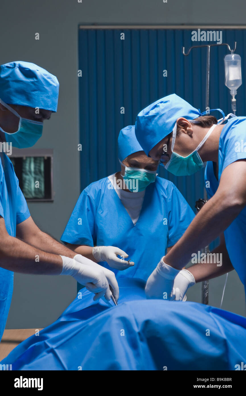 Three surgeons performing a surgery in an operating room Stock Photo ...