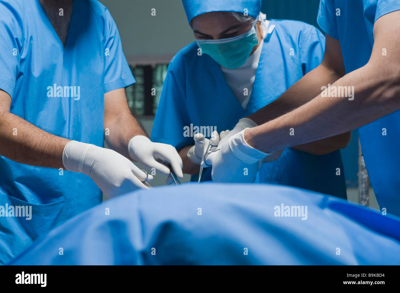 Three surgeons performing a surgery in an operating room Stock Photo ...