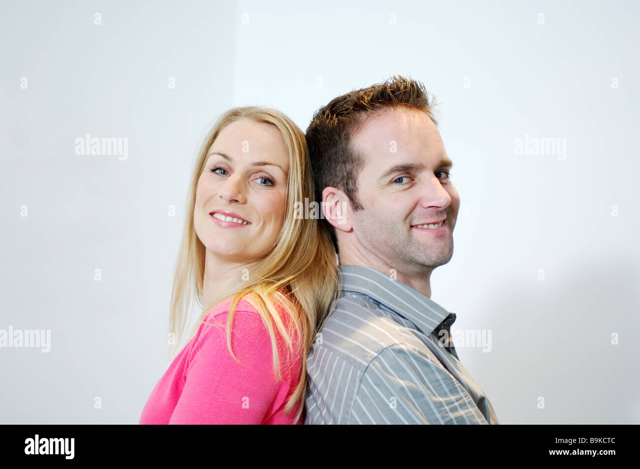 woman and man sitting back to back smiling Stock Photo - Alamy