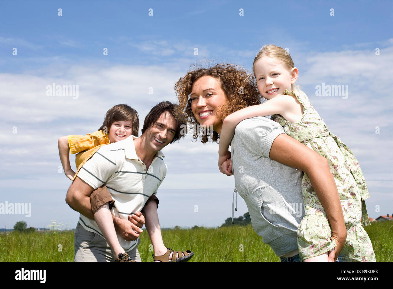 young parents giving their children piggyback ride Stock Photo - Alamy