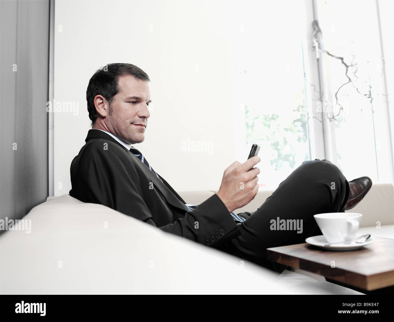 portrait of businessman checking his mobile phone for text messages ...