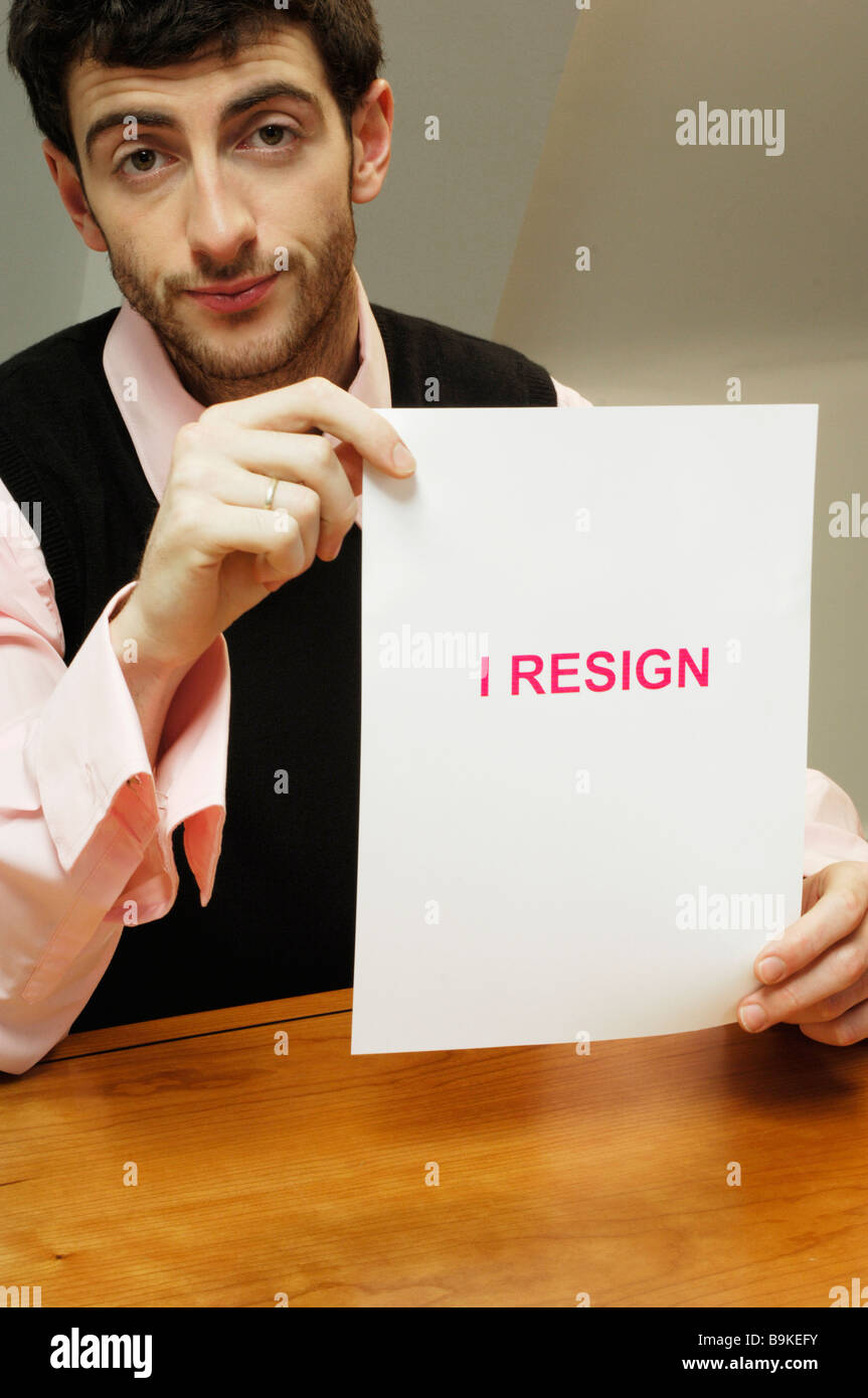 portrait of frustrated businessman sitting at desk holding resign ...