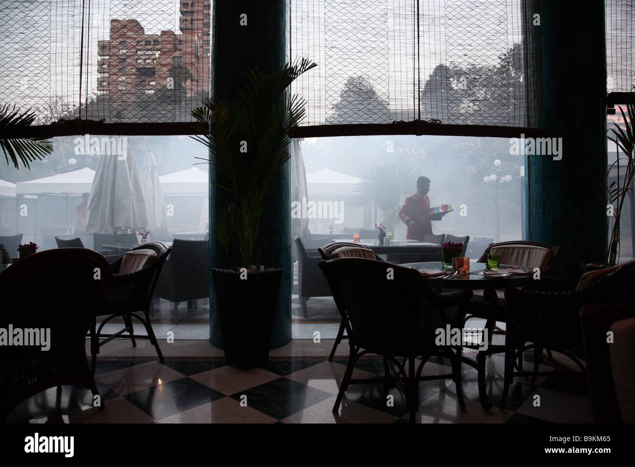 A waiter carries candles to a restaurant table while a fog of insect ...