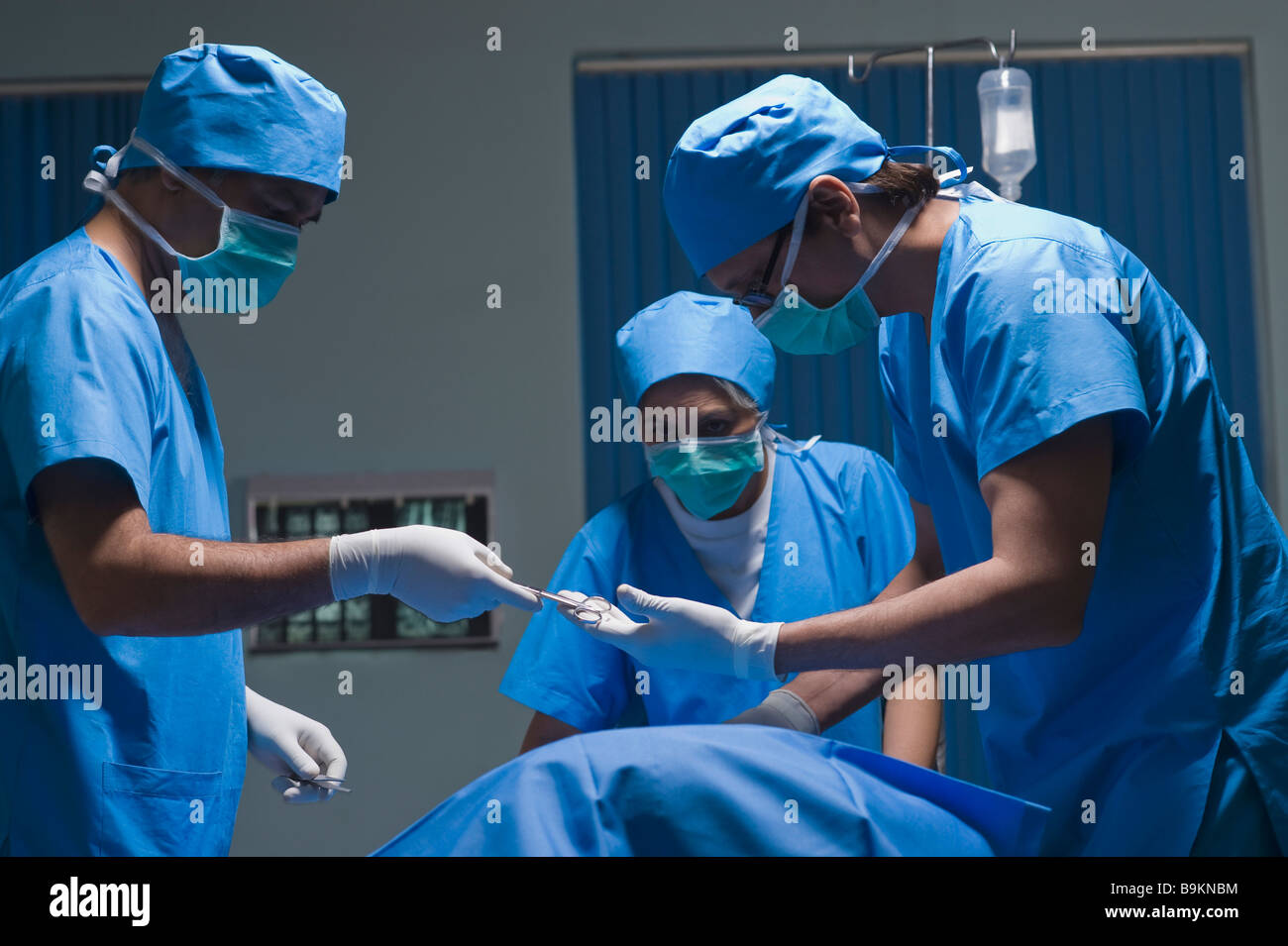 Three surgeons performing a surgery in an operating room Stock Photo ...