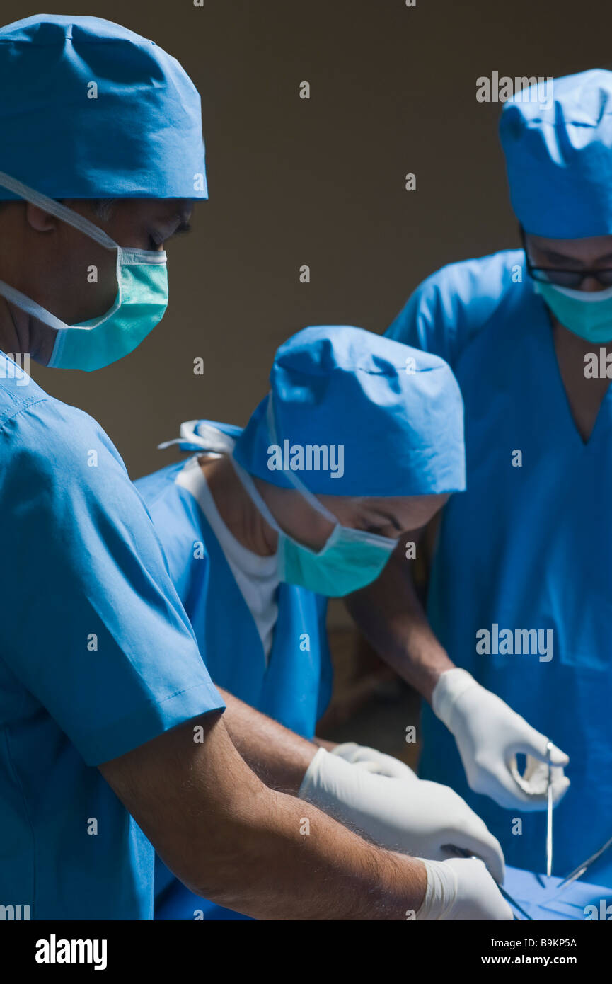 Three surgeons performing a surgery in an operating room Stock Photo ...