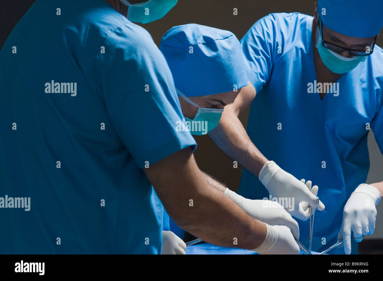 Three surgeons performing a surgery in an operating room Stock Photo ...