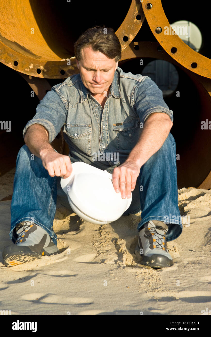 A portrait of a depressed and dejected construction worker sitting in ...