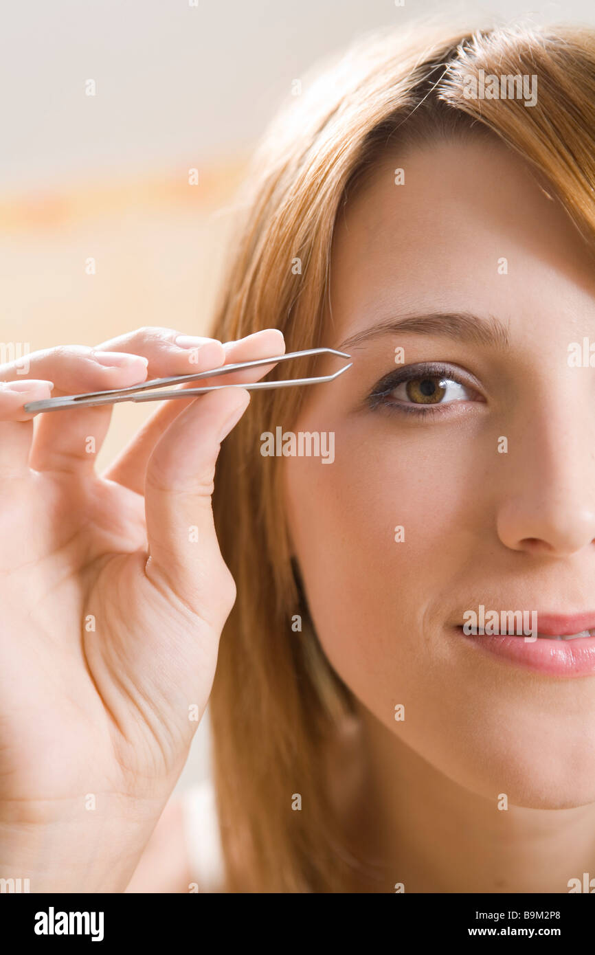 Young woman plucking her eyebrows Stock Photo - Alamy