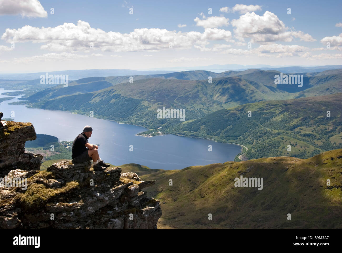 A hiker looks out at the stunning view from the summit of Ben Lomond on ...