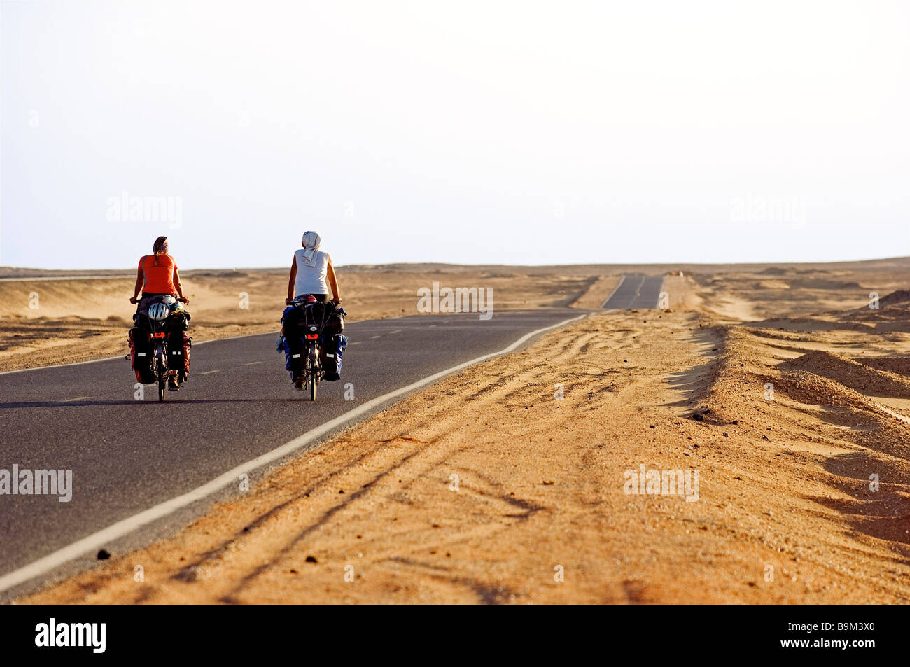 Egypt, Libyan Desert, tourists couple cycling on the Cairo road towards ...