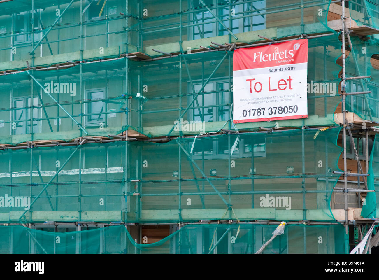 Scaffolding and netting around a large building up to let at the ...