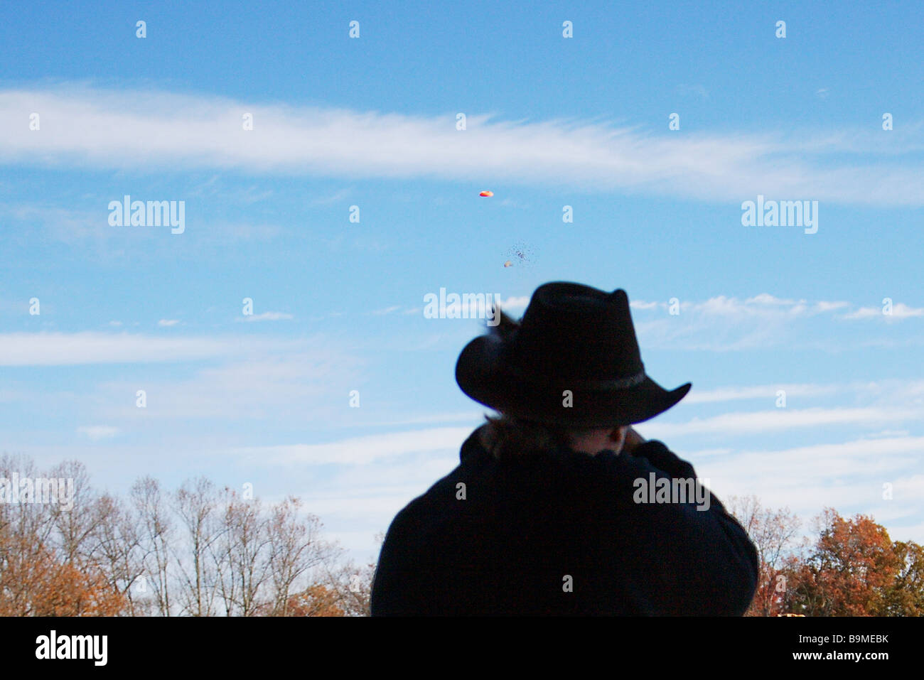 Hunter firing shotgun at clays Clay exploding Stock Photo - Alamy