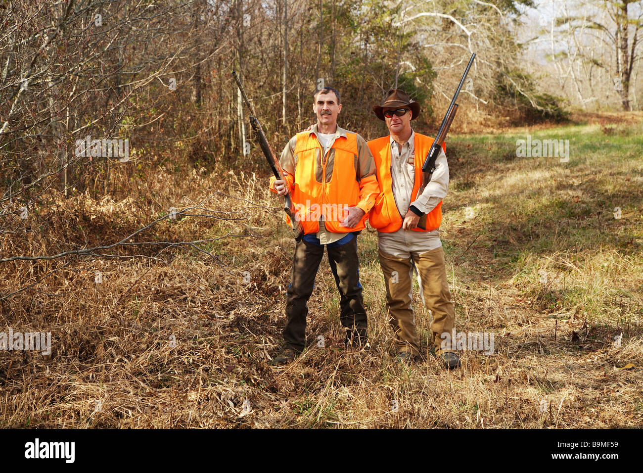 Two hunter in orange safety vests holding shotguns Stock Photo - Alamy